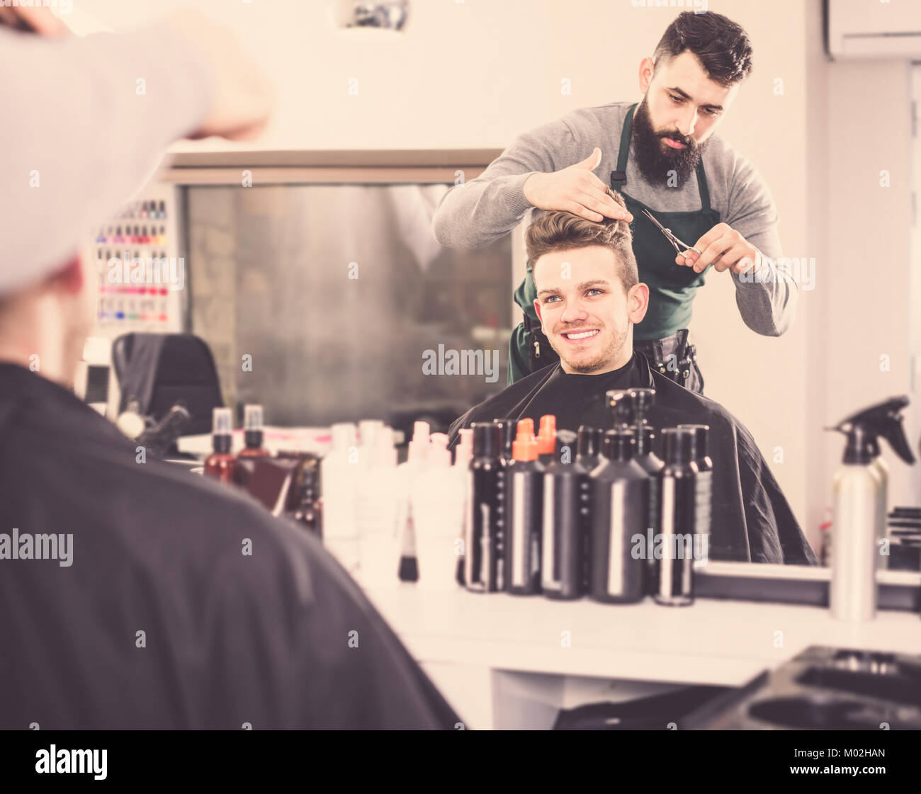 Young guy stylist creating new haircut for man client at hairdressing ...