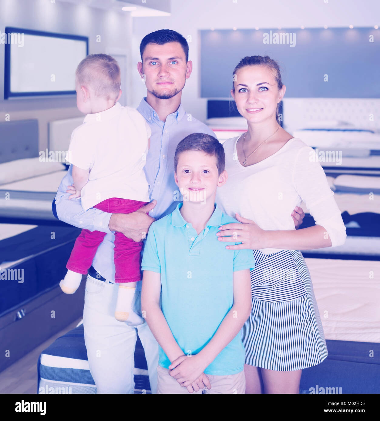 Portrait of cheerful family visiting furniture salon in search of new ...