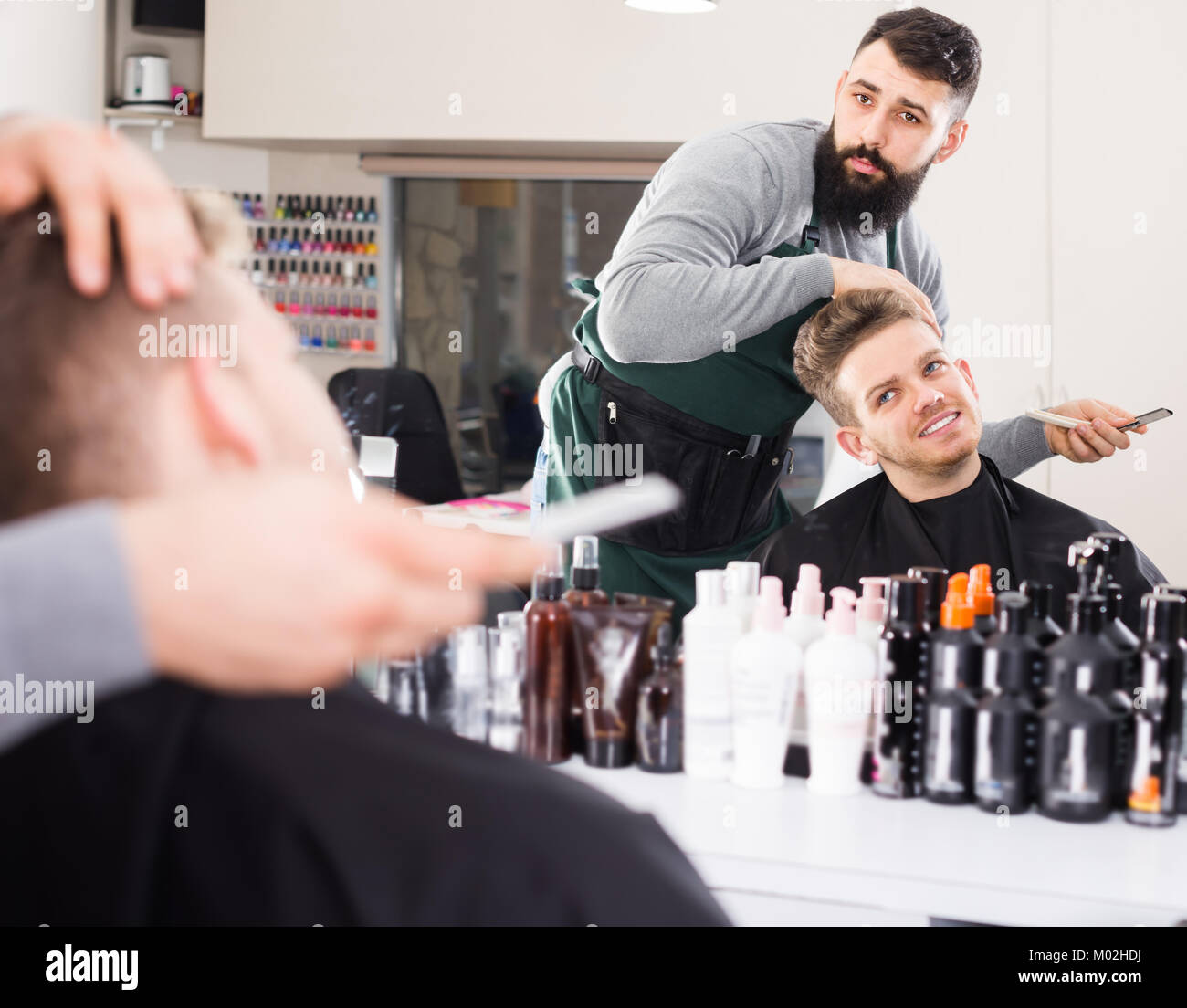 Smiling man hairdresser making haircut to client at hair salon Stock ...