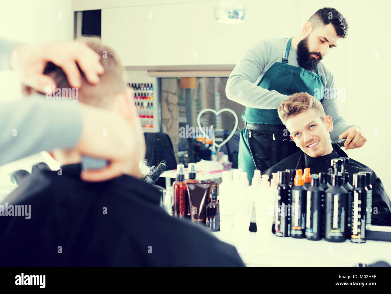 Man hairdresser doing new haircut for happy young guy client at hair ...