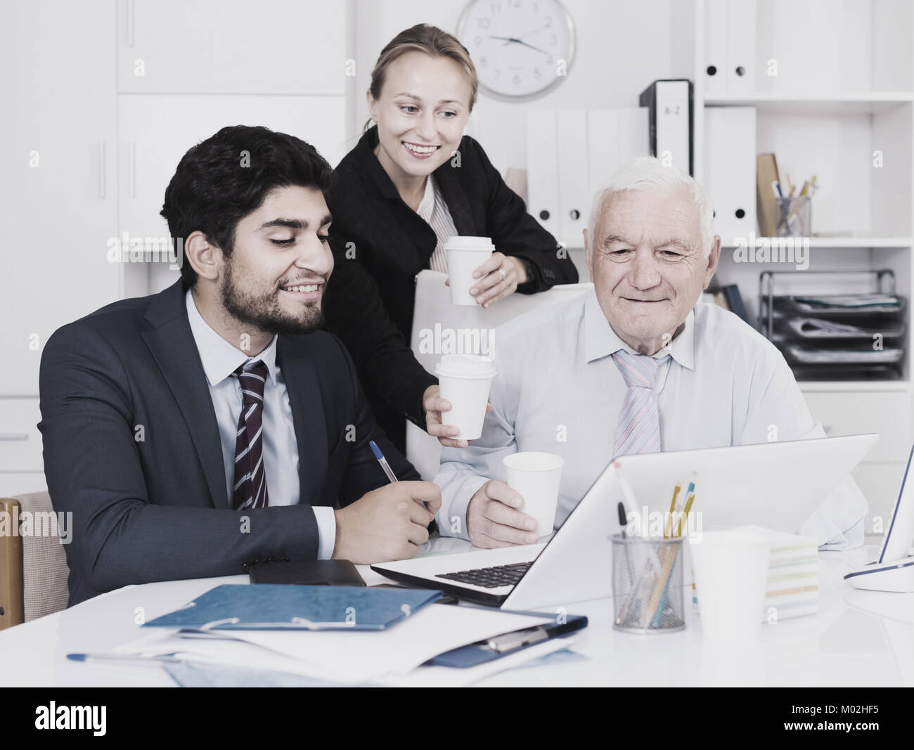 Office workers are demonstrating reports on laptop to mature boss in ...