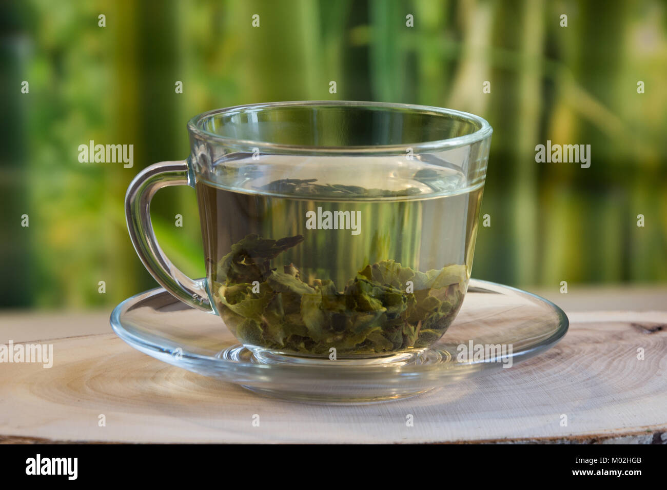 Cup with green tea and green leaves on nature blur background on wooden ...