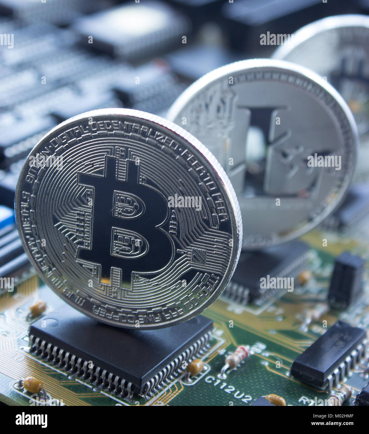 On a printed circuit board are silver coins of a digital crypto ...