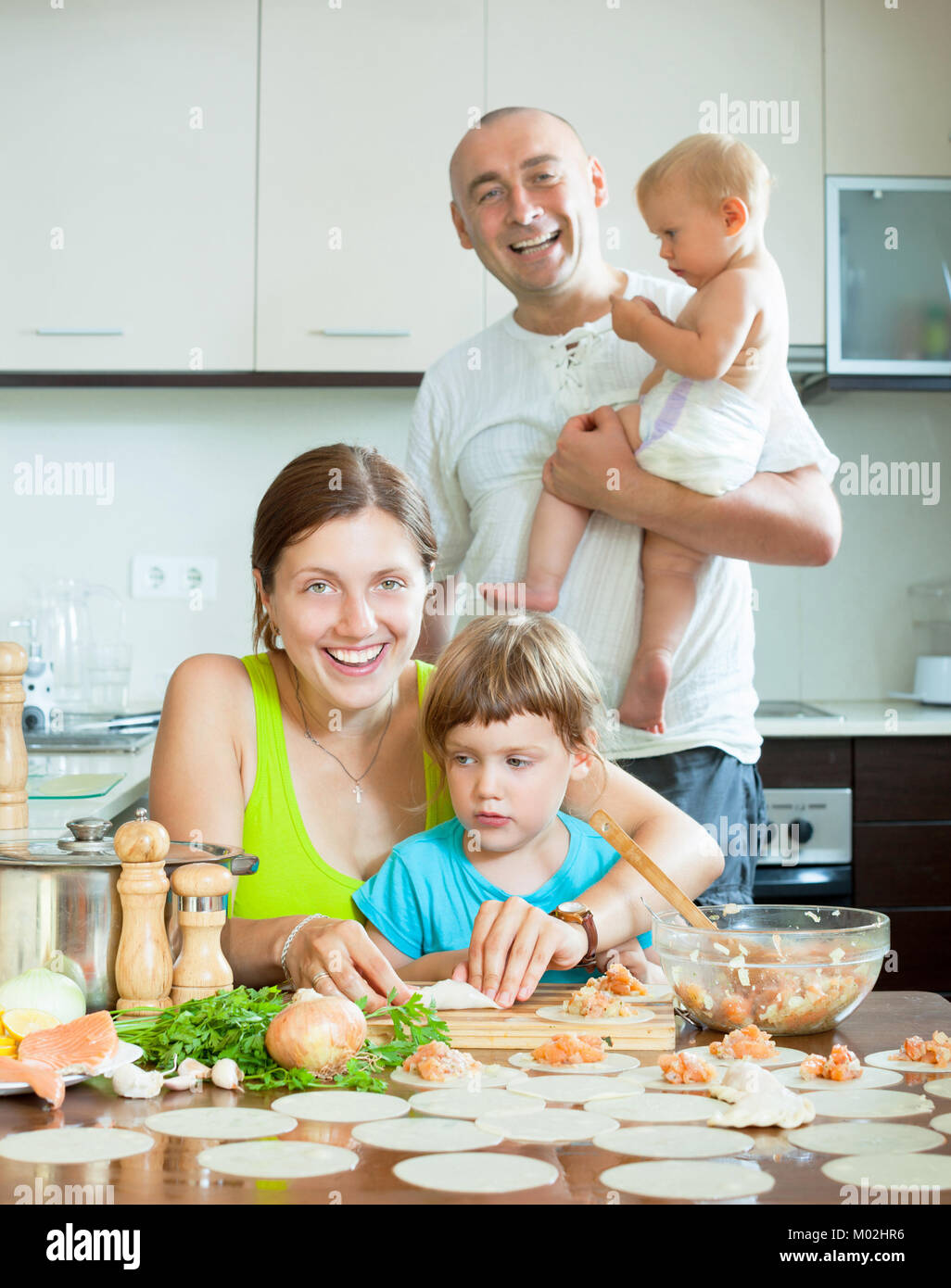 Happy family of four in the kitchen prepares food Stock Photo - Alamy