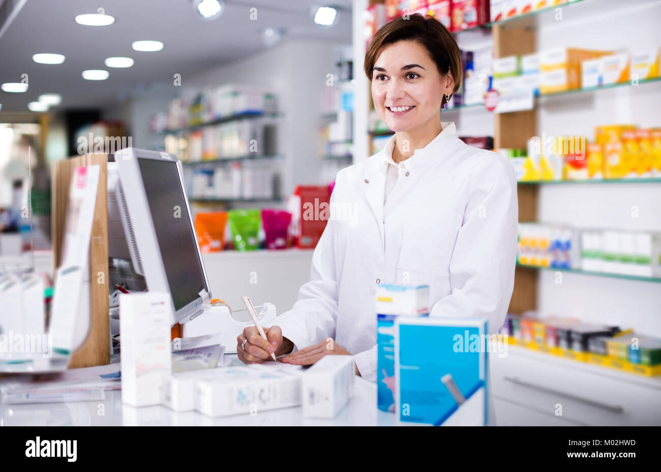 Smiling pharmacist ready to assist in choosing at counter in pharmacy ...