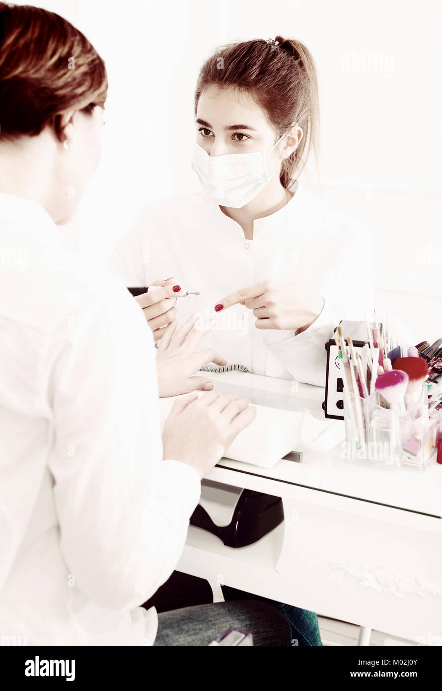 Positive woman doing manicure in shellac technique in nail salon Stock ...