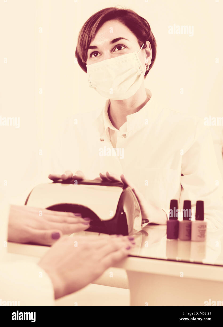 Satisfied pleasant smiling female client doing nails in shellac ...