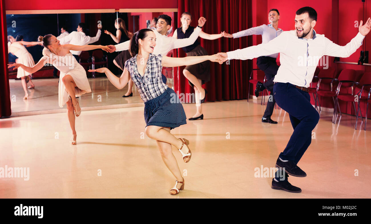 Happy dancing couples enjoying active swing in modern studio Stock ...