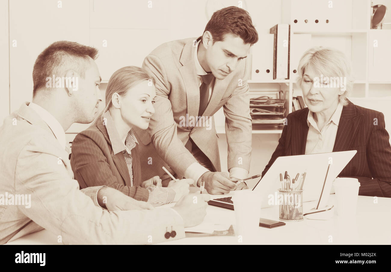 Focused serious business team working with computer in modern office ...