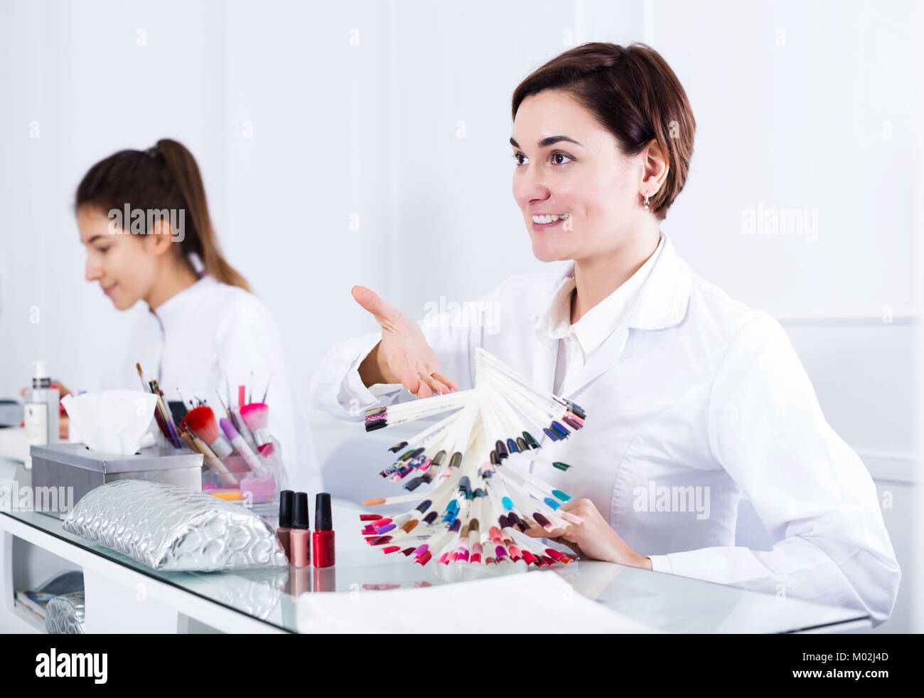 Pretty young woman doing nails displaying polish color schemes in nail ...