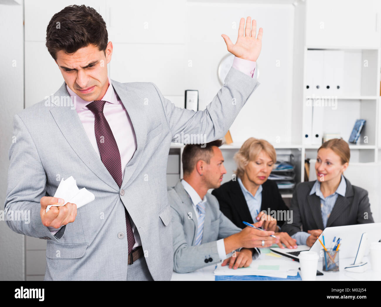 Irritated businessman standing in modern office on background of ...