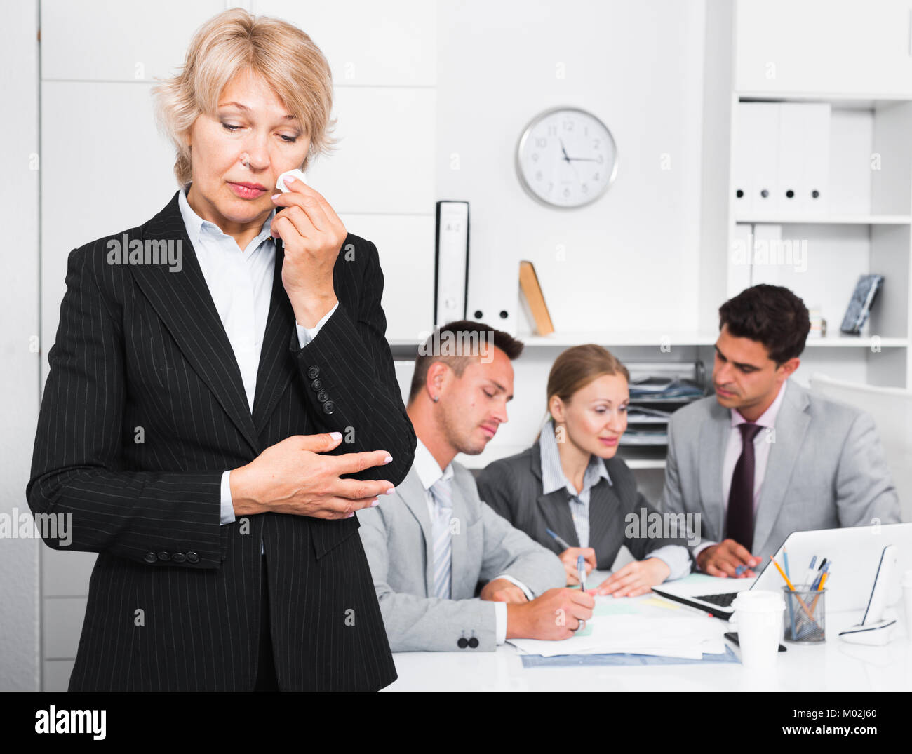 Unhappy and crying woman standing at office on background with ...