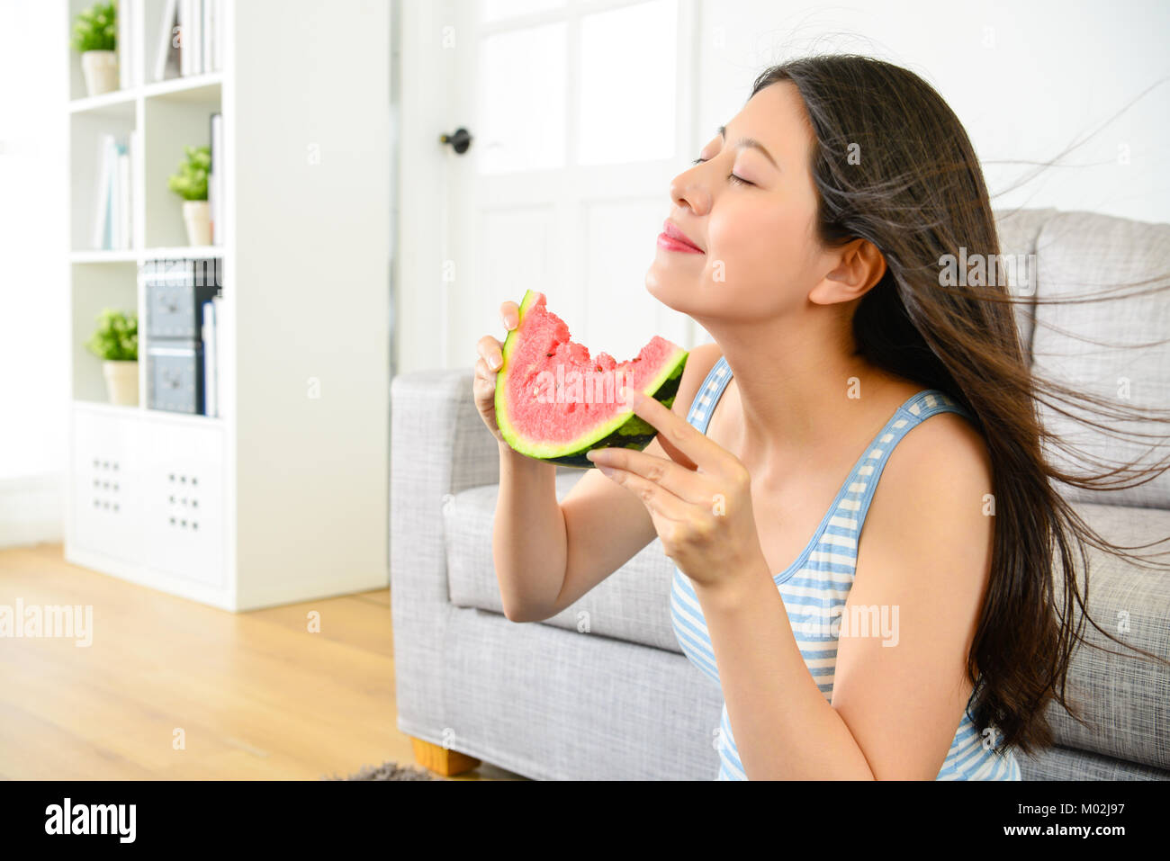 elegant young woman enjoying sweet watermelon and feeling refreshing in ...