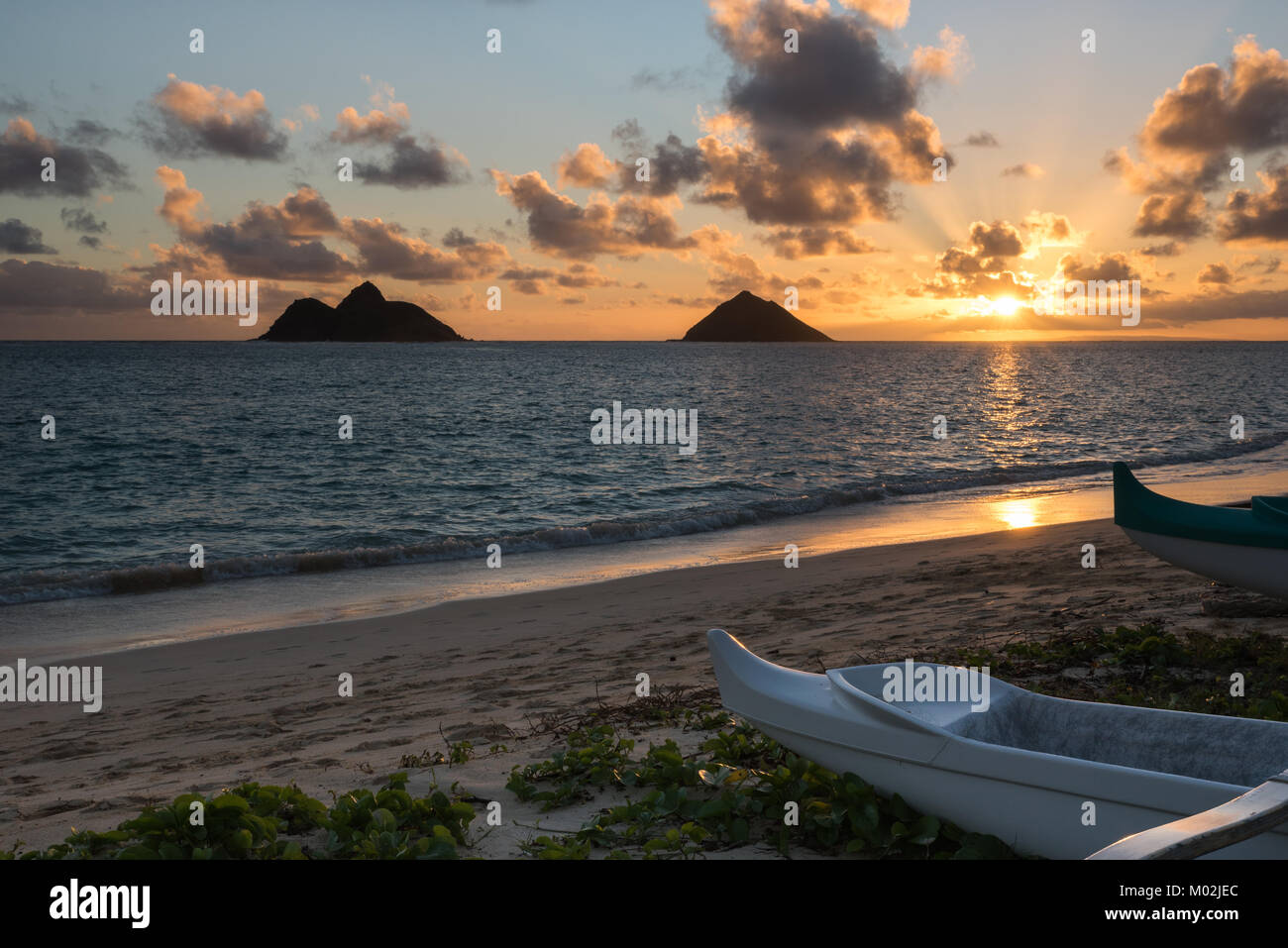 Sunrise over Mokulua Islands from Lanikai Beach with canoes in ...