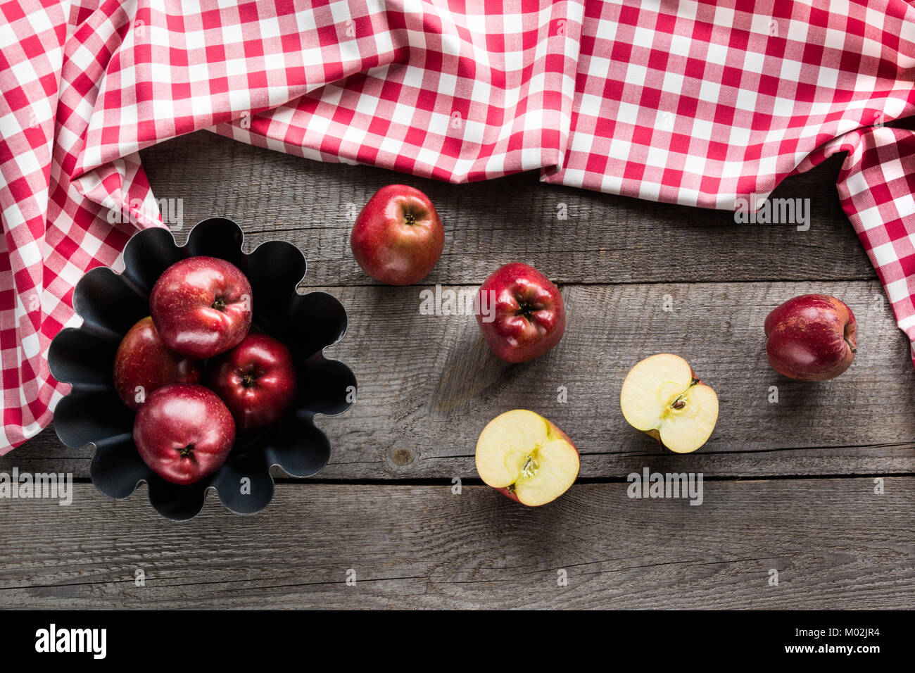 Ripe red apples in baking form on wooden board with red checkered ...