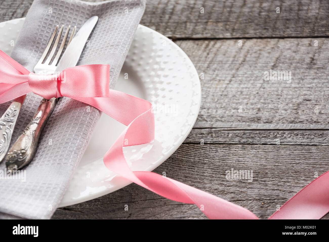 Elegance table setting with pink ribbon for romantic dinner on wooden ...