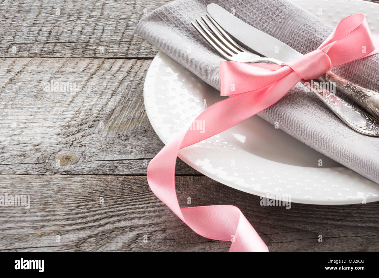 Elegance table setting with pink ribbon for romantic dinner on wooden ...
