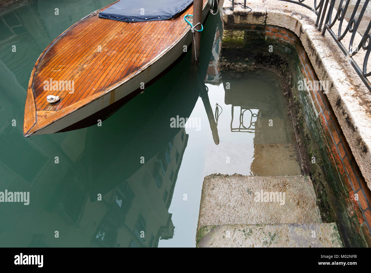 wooden boat parked near entrance steps in Venice city channel Stock ...