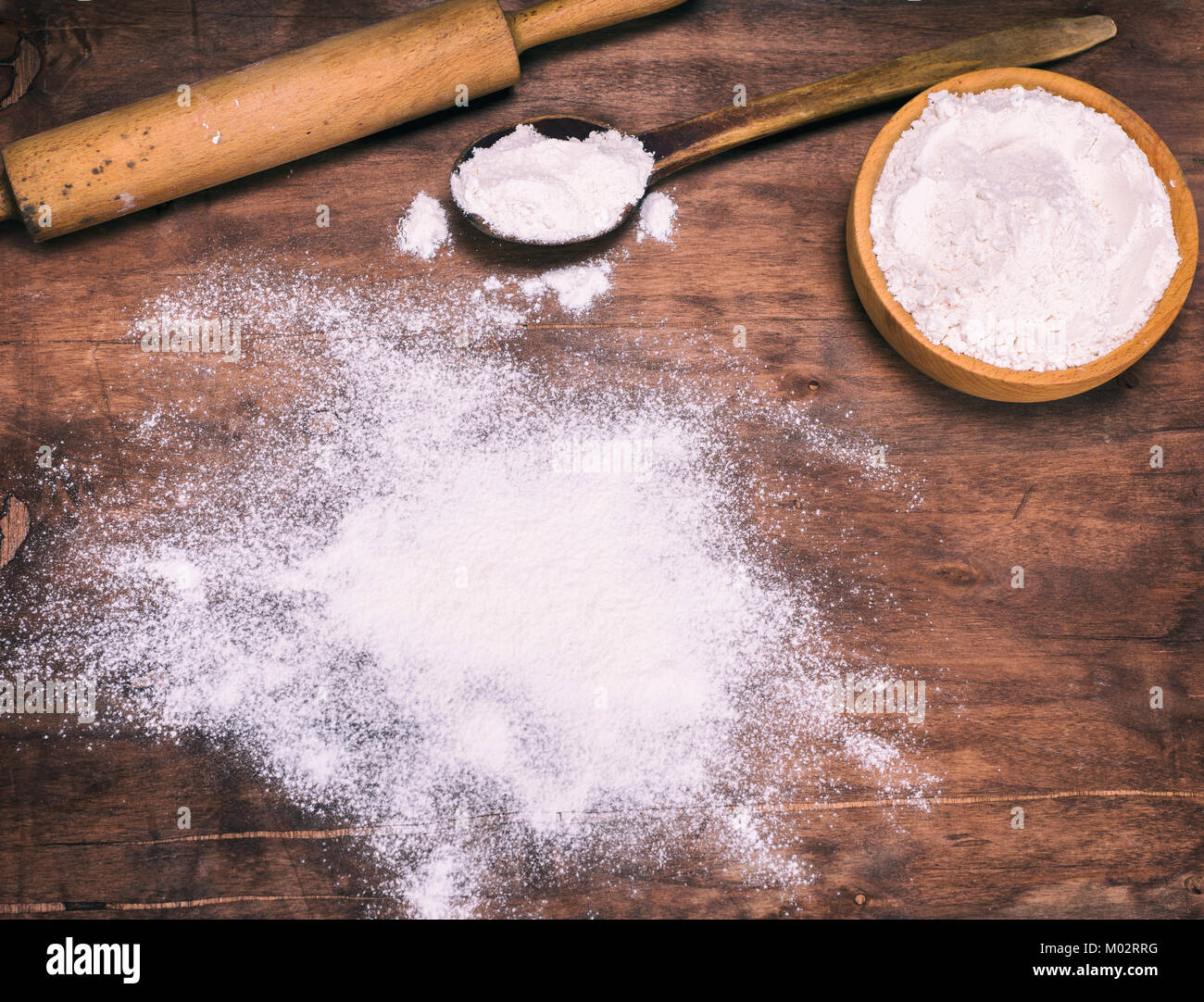 scattered white wheat flour on a brown wooden background, next to a ...