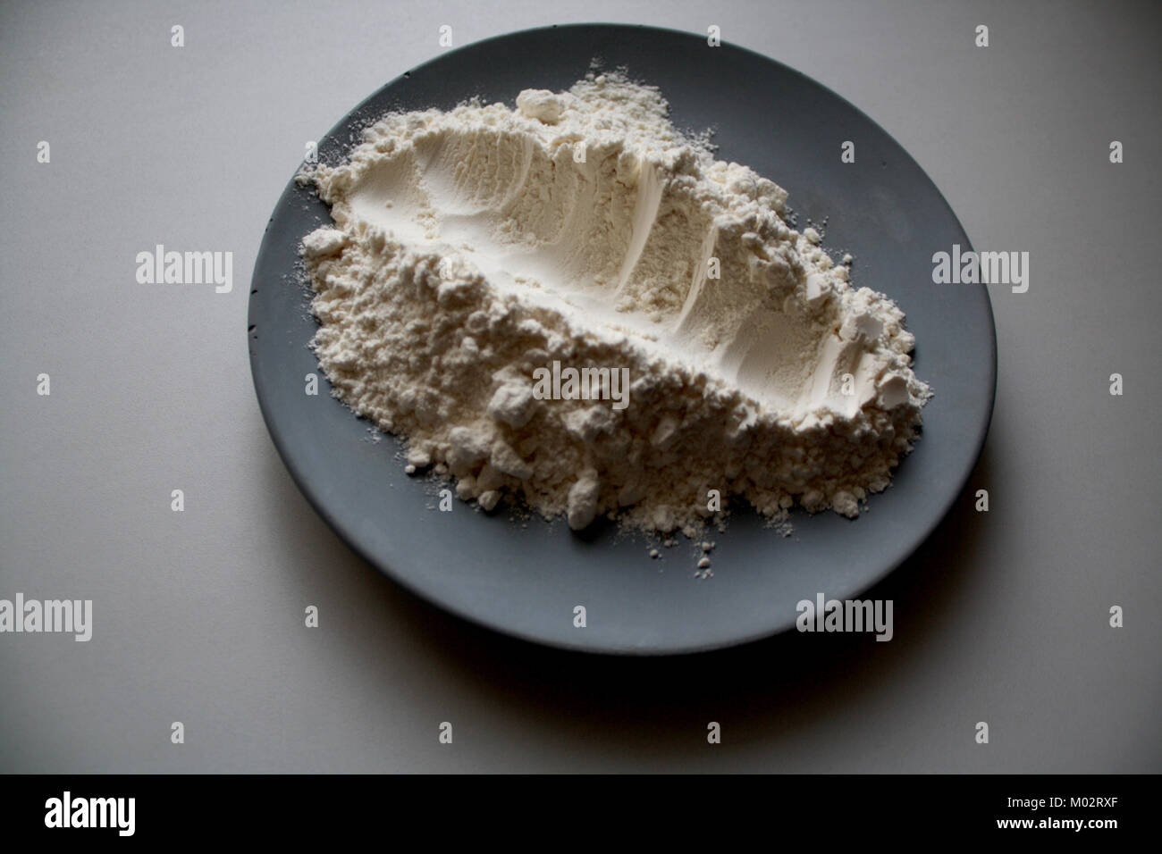 Heap of wheat flour divided with ditch isolated on grey concrete plate ...