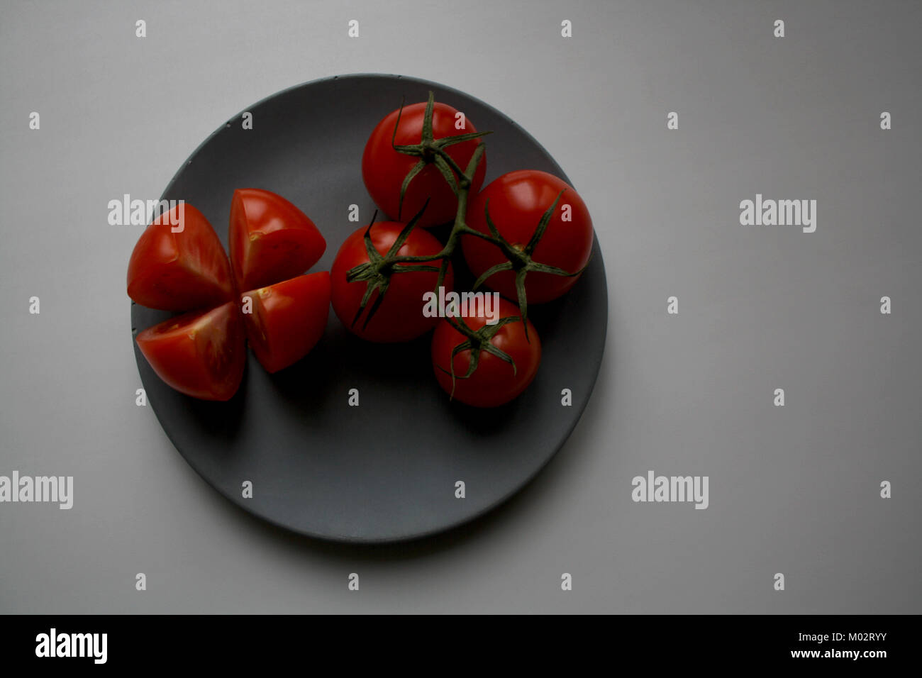 Five tomatoes isolated on a grey concrete plate from a high angle view ...