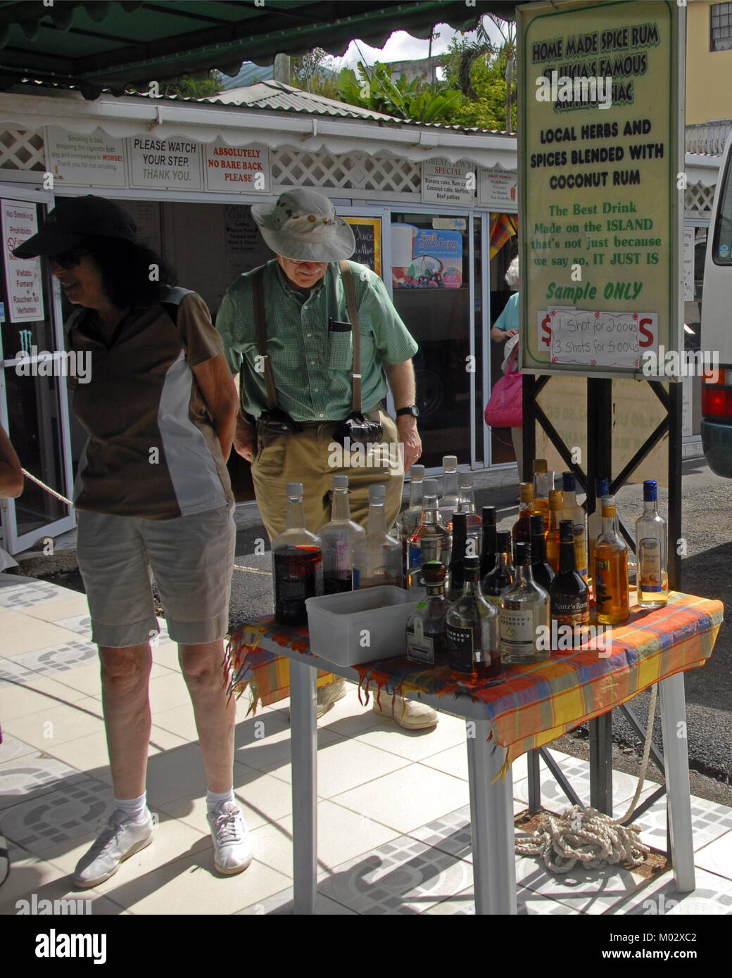 Tourist looking at table with display of rum samples, St Lucia ...