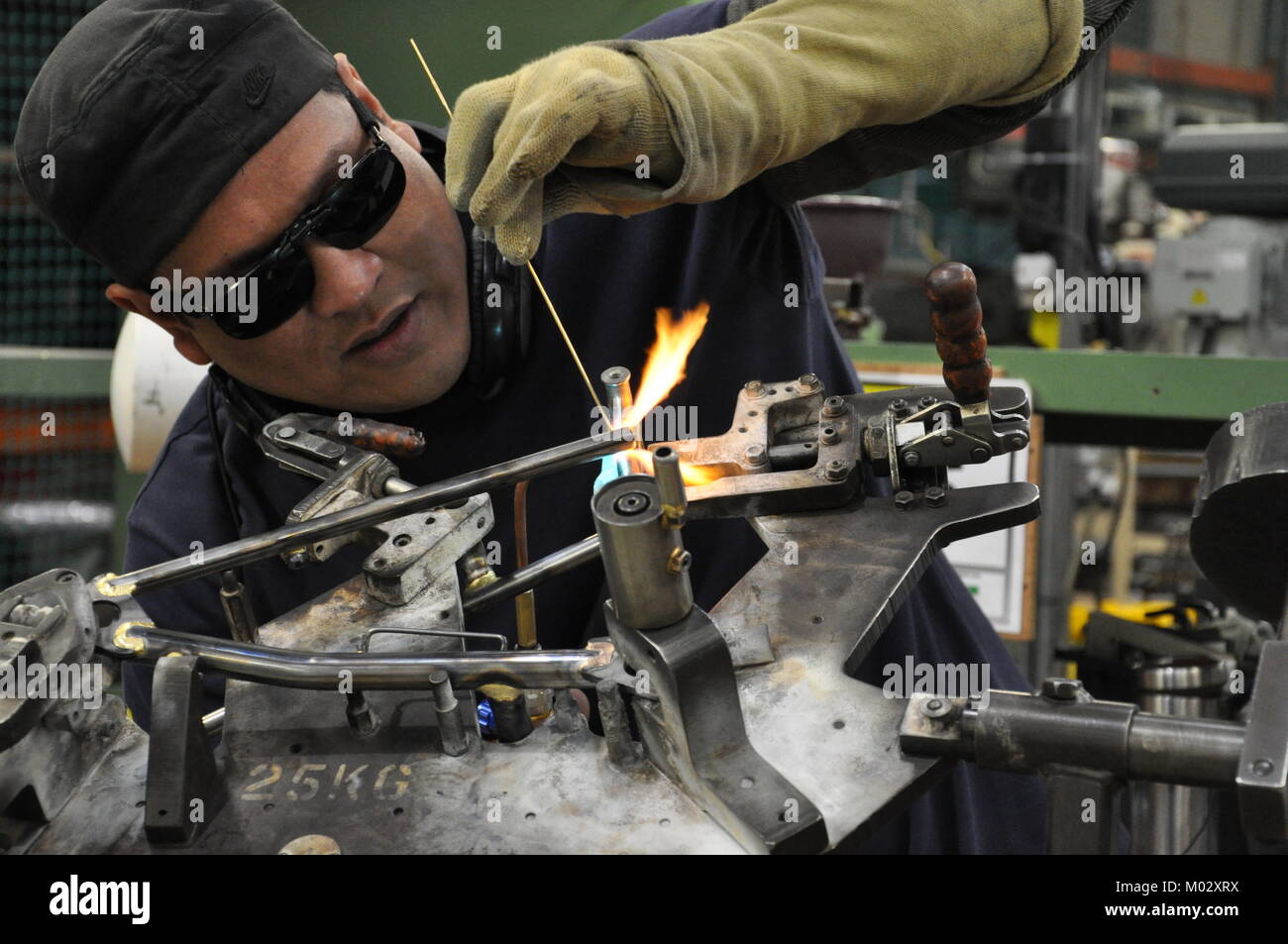 Welder working on steel bicycle frame in a UK factory with flame ...
