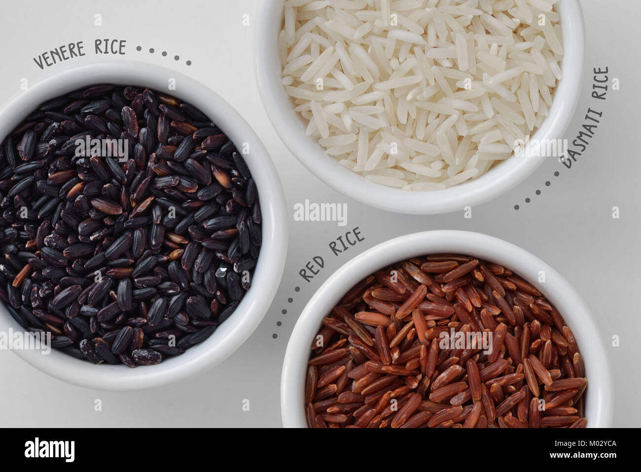 Venere rice, red rice and basmati rice in bowls on wooden background ...