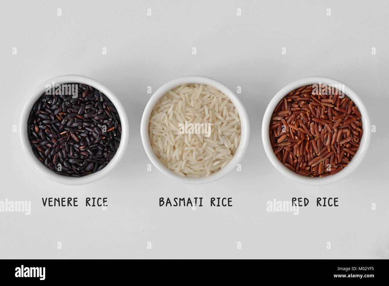 Venere rice, red rice and basmati rice in bowls on white background ...