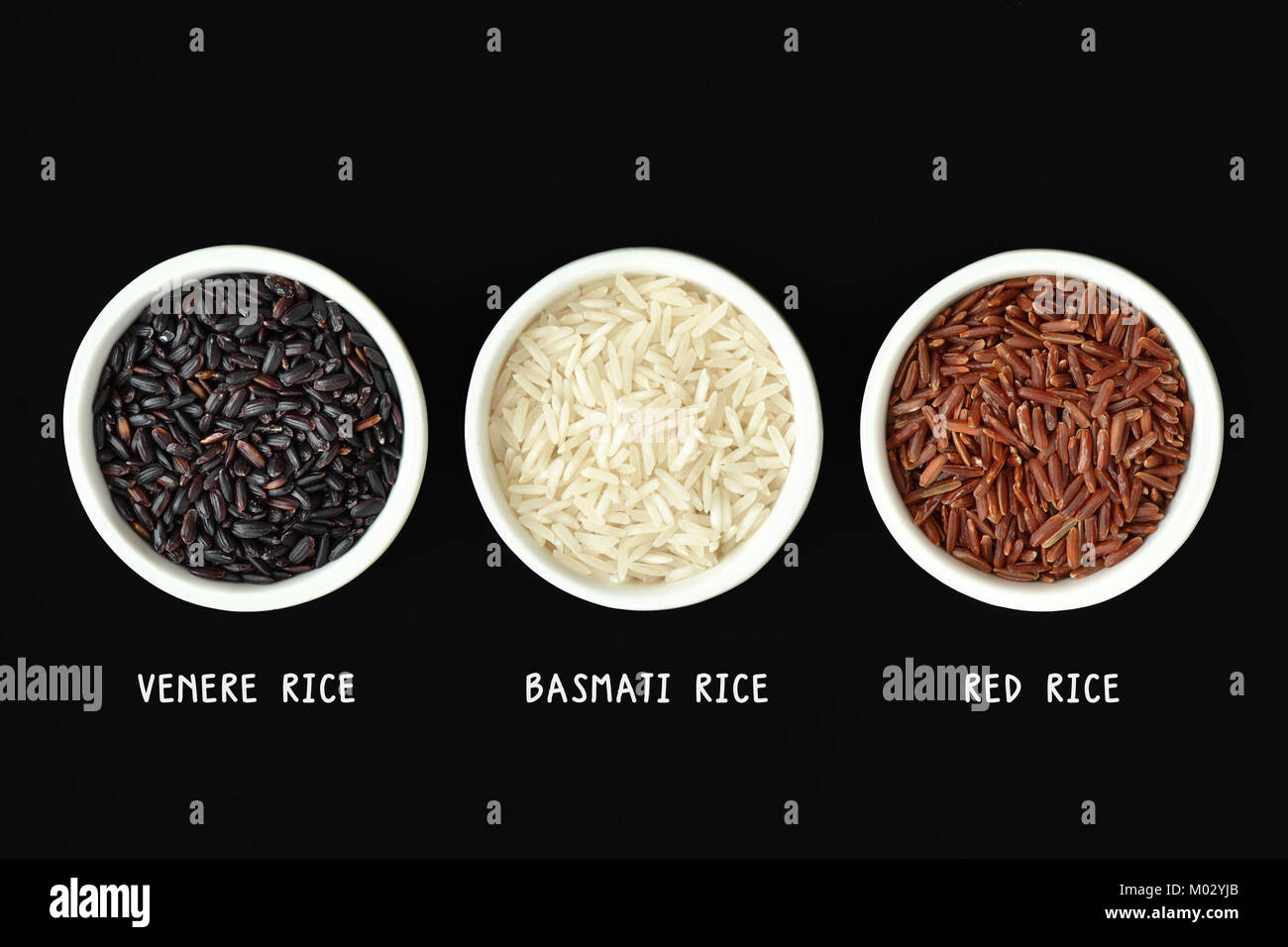 Venere rice, red rice and basmati rice in bowls on black background ...