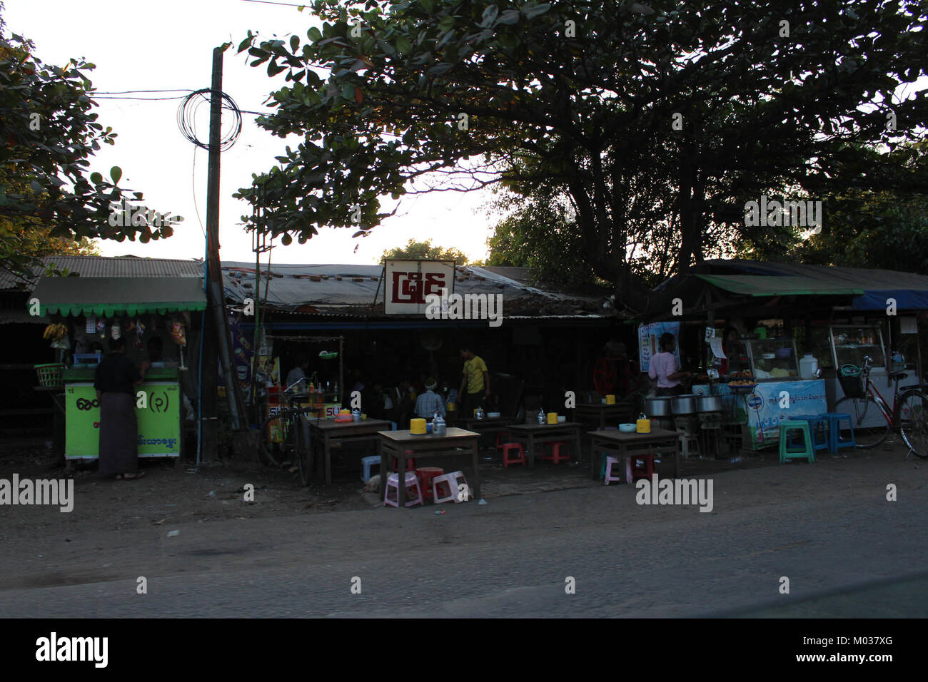 This image captures a local café in the suburbs of Yangon, Myanmar, providing a glimpse into the ...
