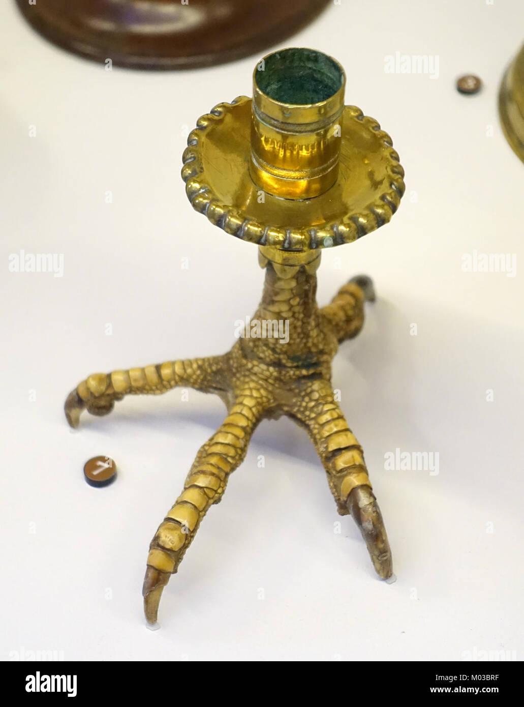 This 1800s brass candlestick, featuring an eagle's claw design, is part ...