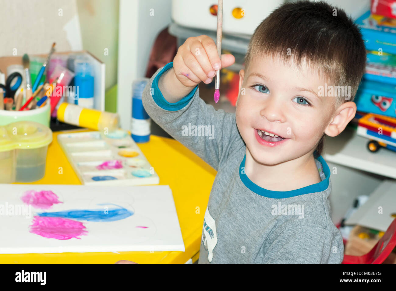 A boy paints a drawing on a piece of paper Stock Photo - Alamy