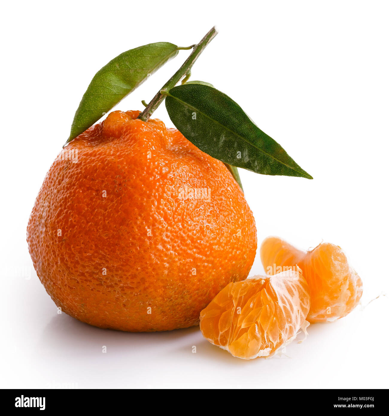 One and half segments of a mandarin next to whole mandarin with leaves ...