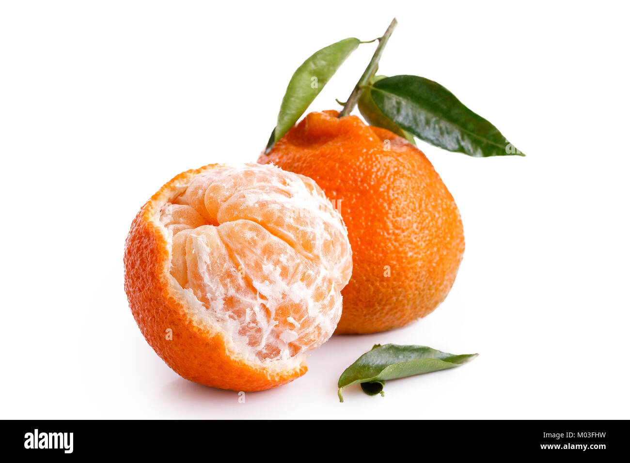 One half peeled and one whole mandarin with leaves isolated on white ...