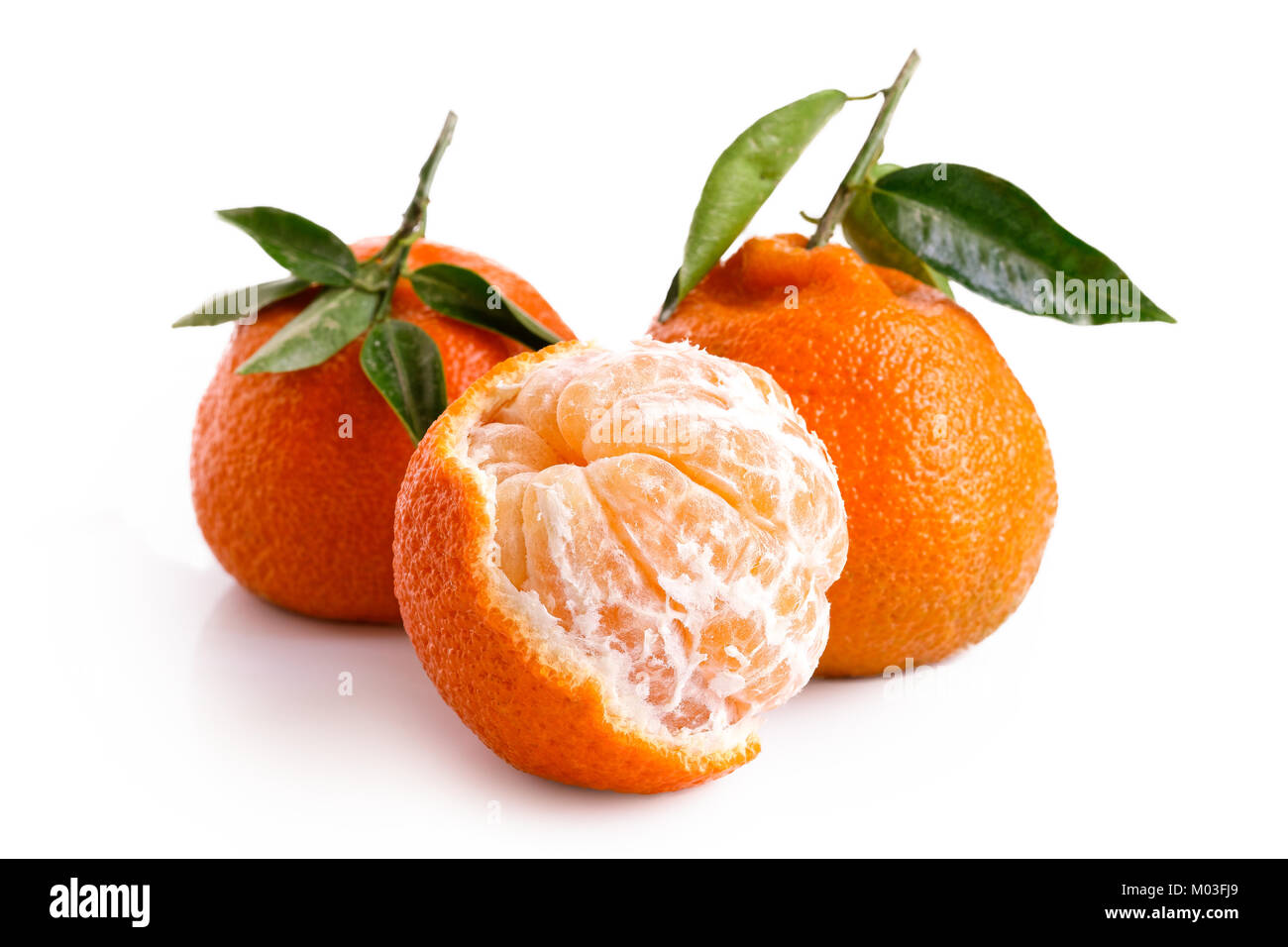 One half peeled and two whole mandarins with leaves isolated on white ...