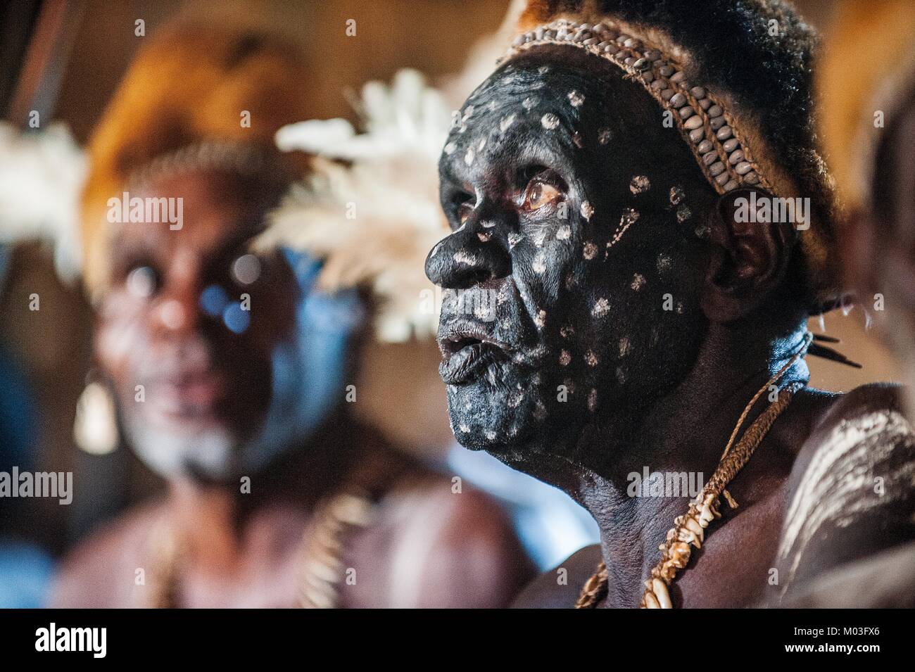 Asmat with a traditional painting on a face, cap from cuscus and ...