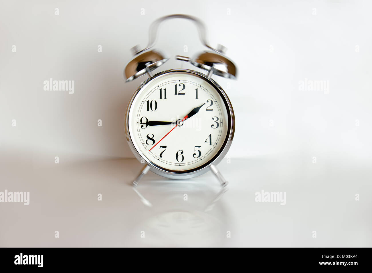 White retro clock isolated against a white background casting a ...