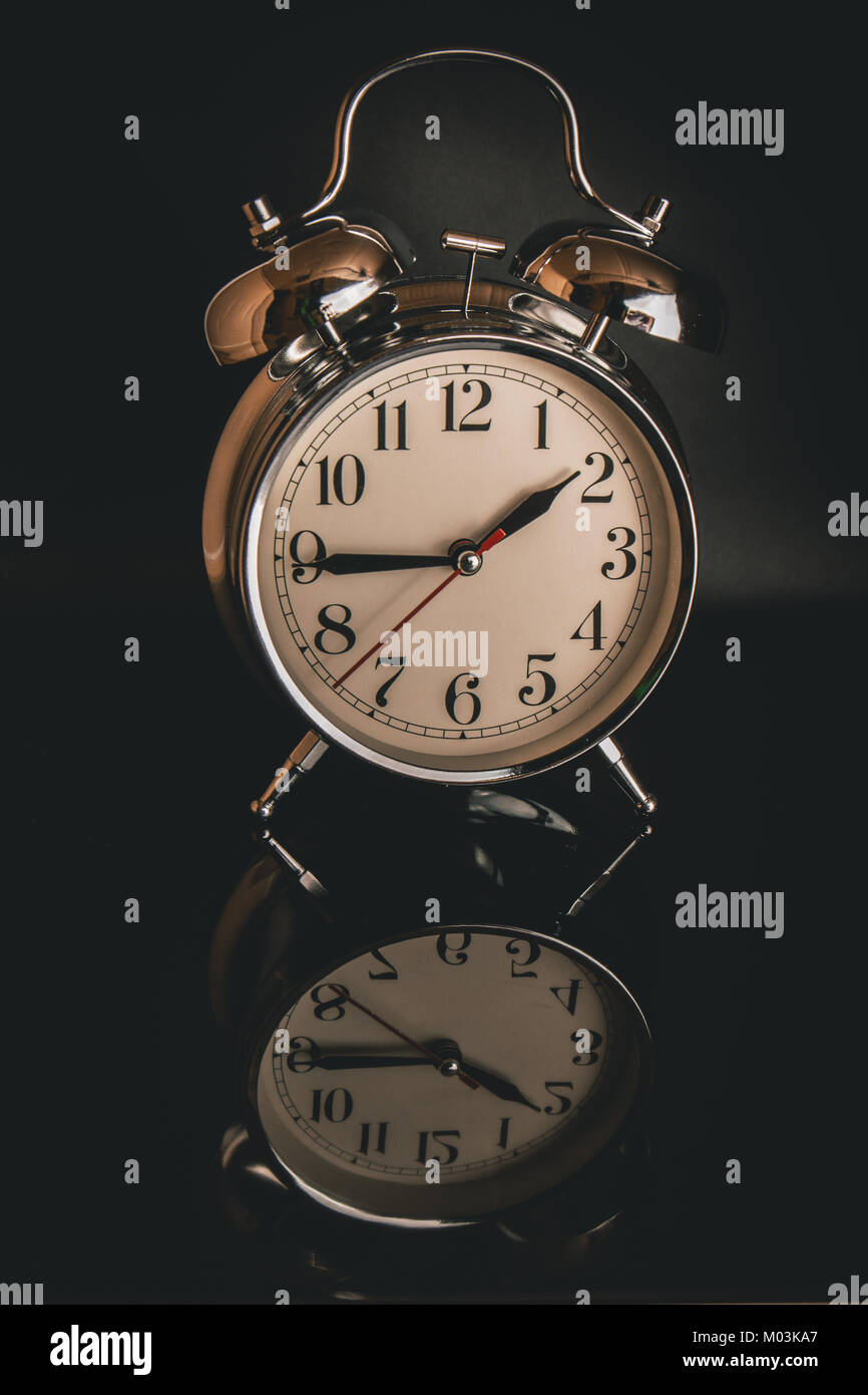 White retro clock isolated against a dark background casting a ...