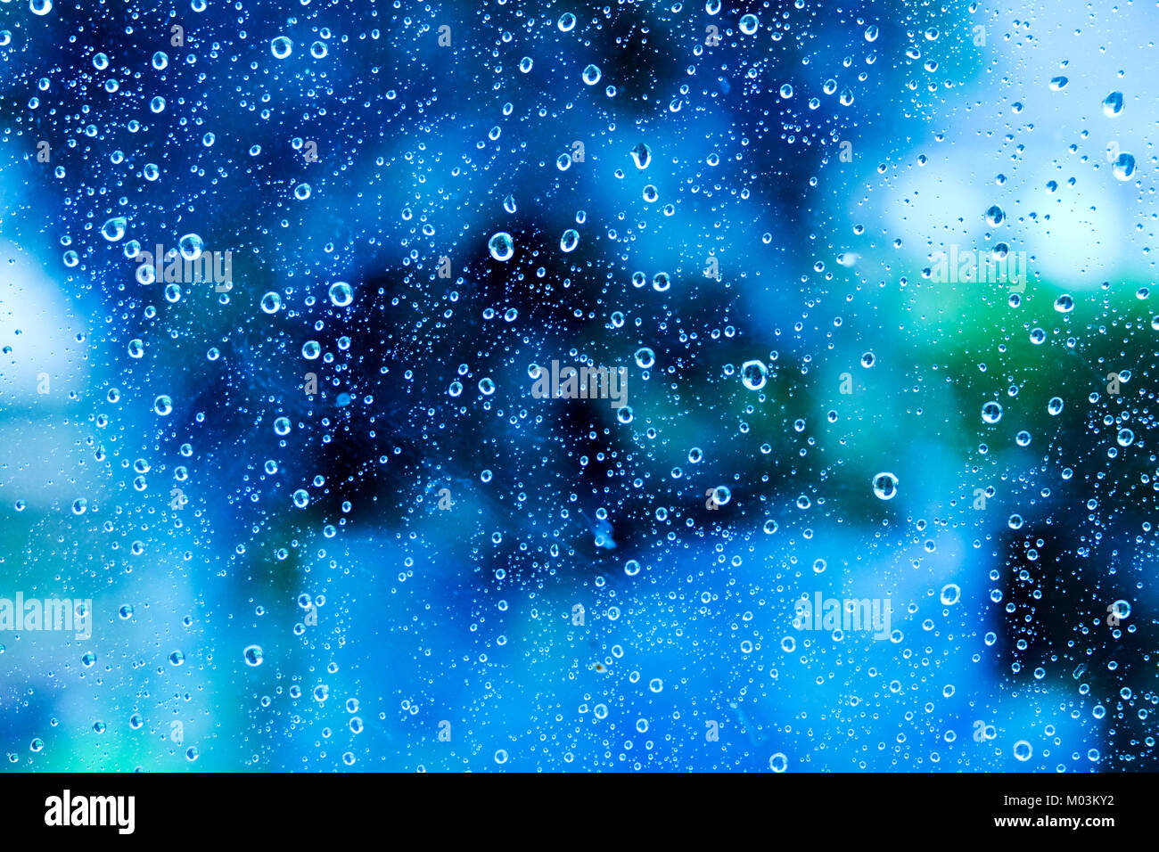 Hundreds of white rain drops on a glass window with a blurred ...