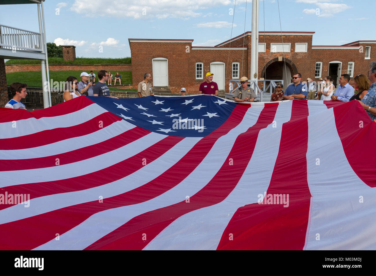 The 15-star, 15-stripe "Star-Spangled Banner" being folded by visitors ...