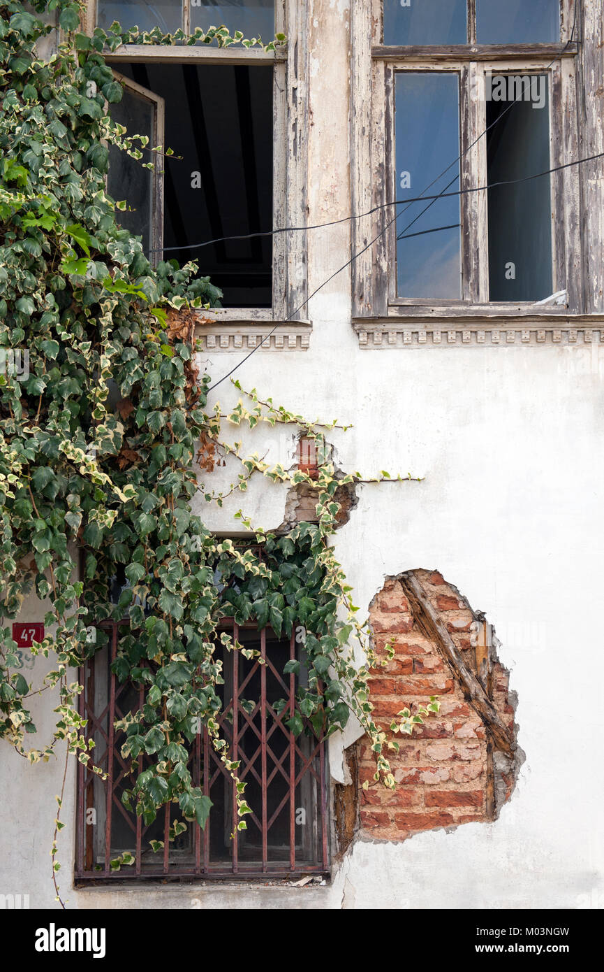 An old, weathered building facade with peeling plaster revealing red ...
