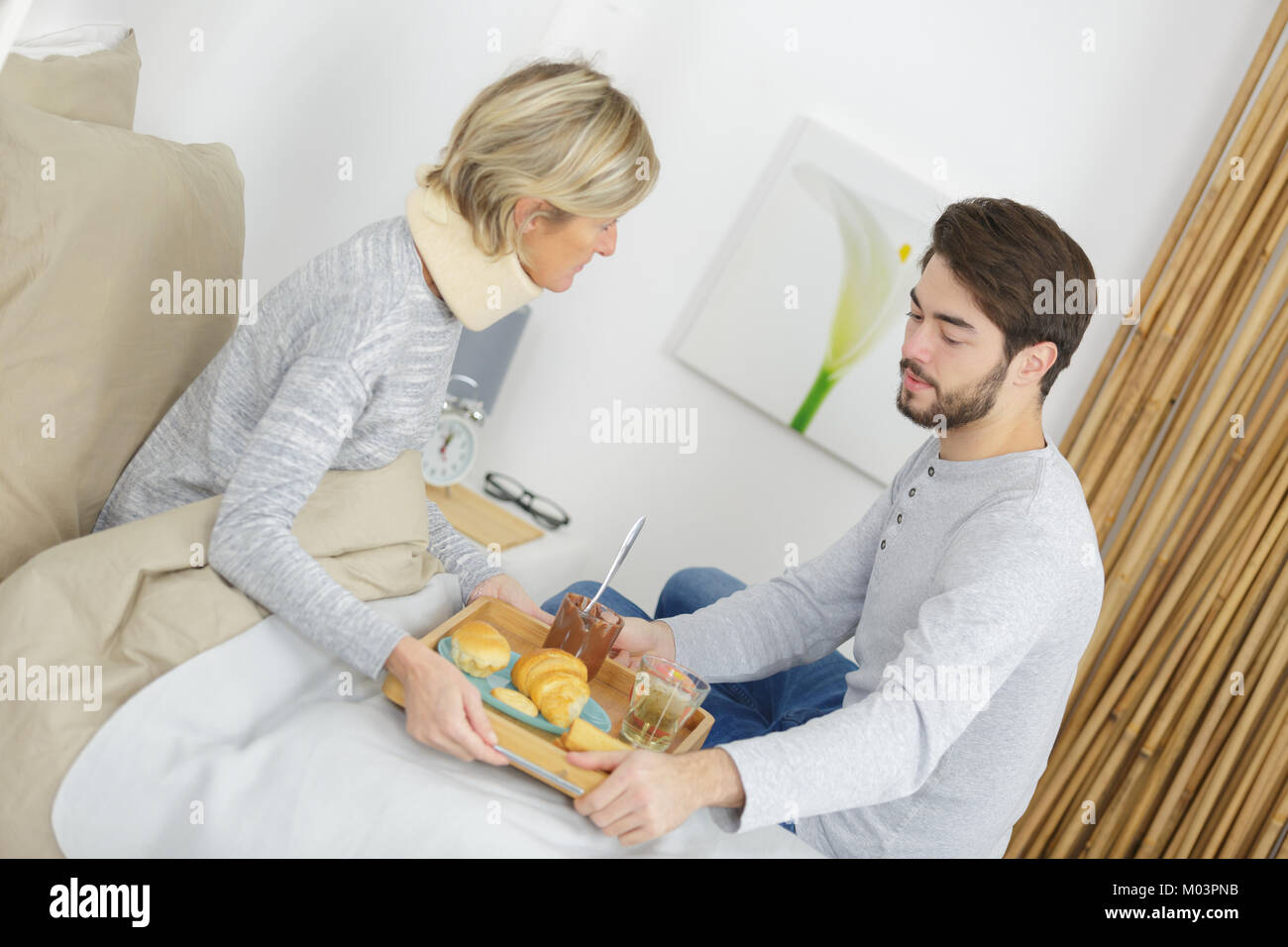 man giving a tray of food to a recovering woman Stock Photo - Alamy