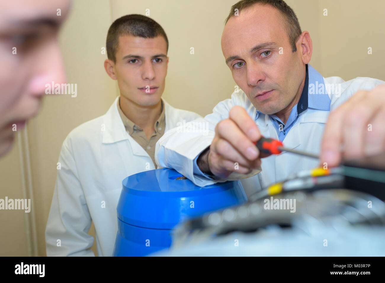 Man using screwdriver, young man watching Stock Photo - Alamy