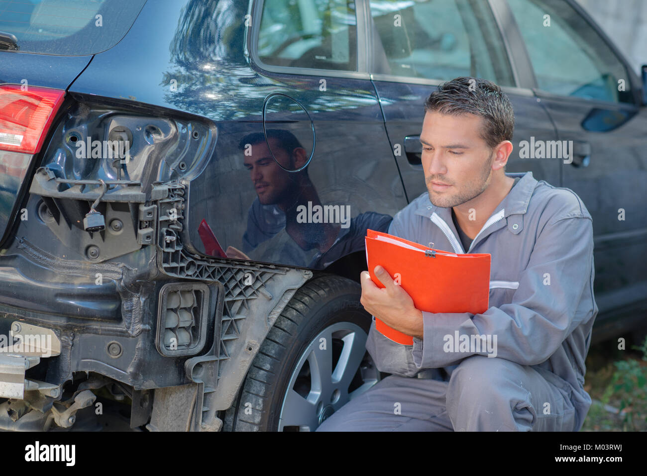 Mechanic inspecting a damaged car Stock Photo - Alamy