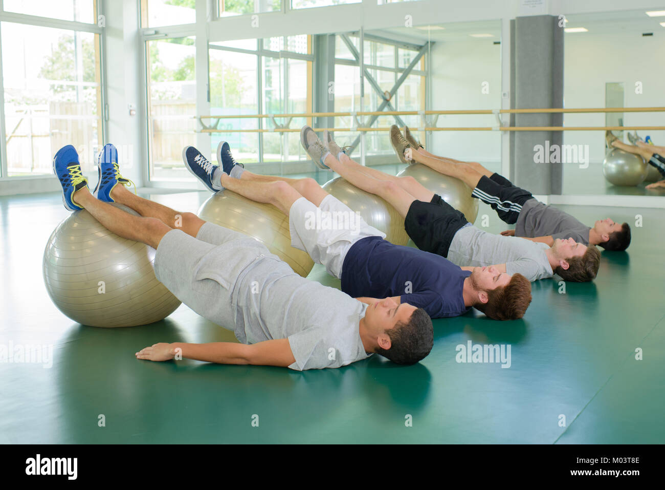 Four men with legs raised on aerobic balls Stock Photo - Alamy