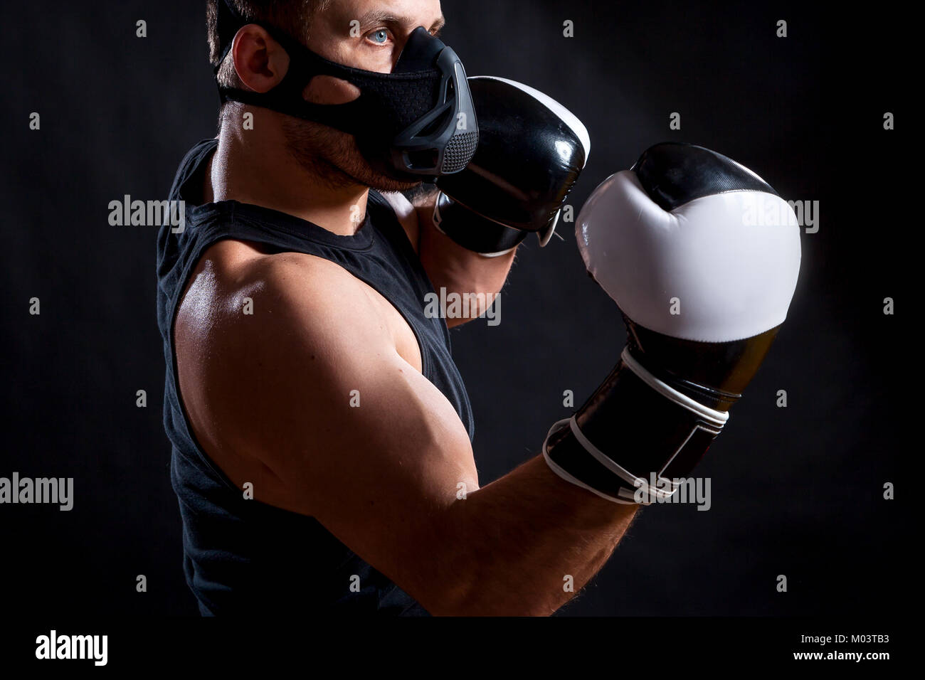 A dark-haired male athlete in a black training mask, sports shirt and ...