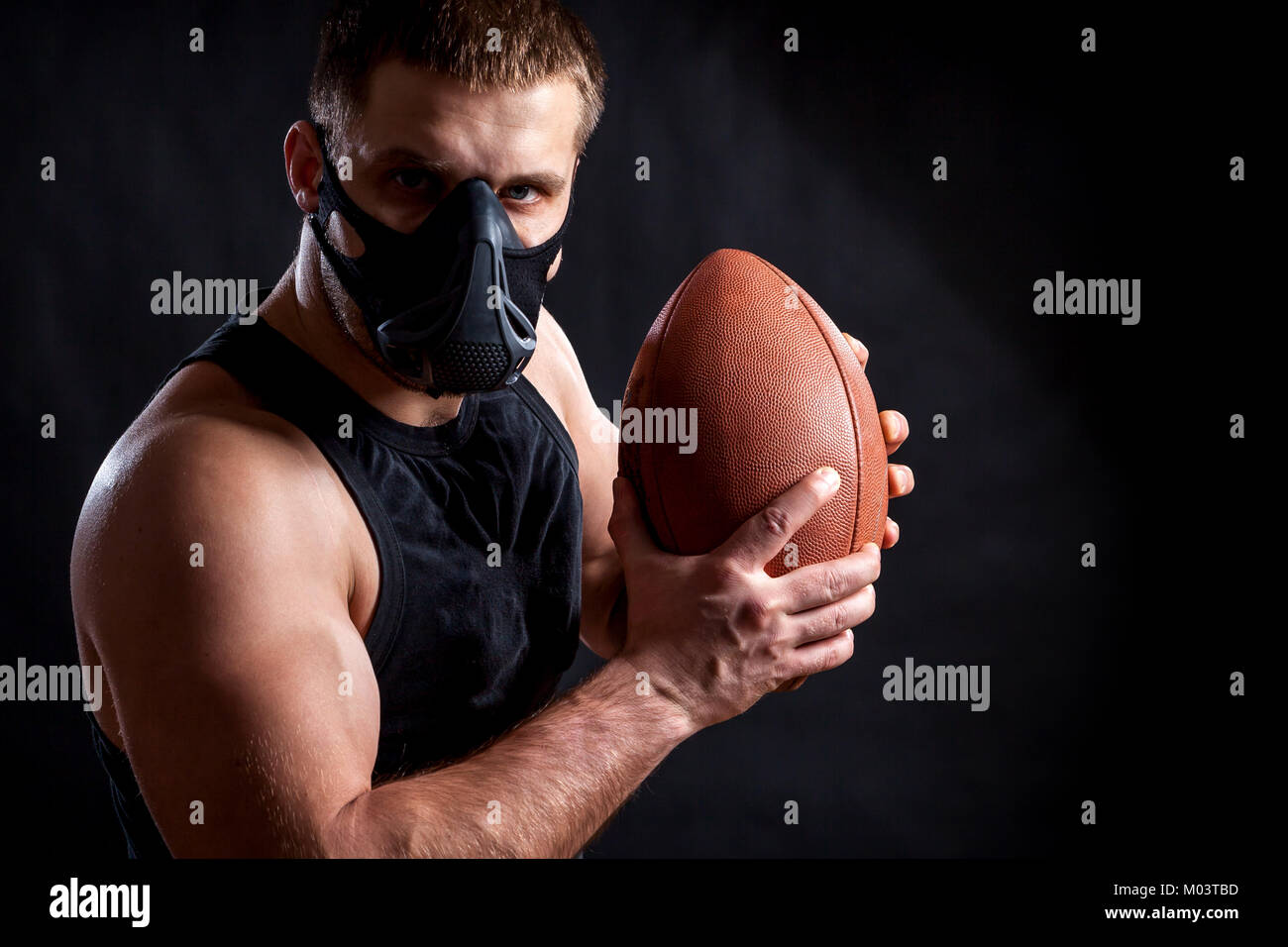 A dark-haired male athlete in a black training mask, a sports shirt ...
