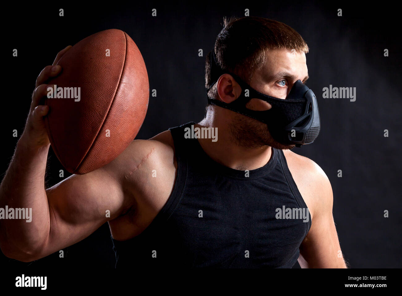 A dark-haired male athlete in a black training mask, a sports shirt ...