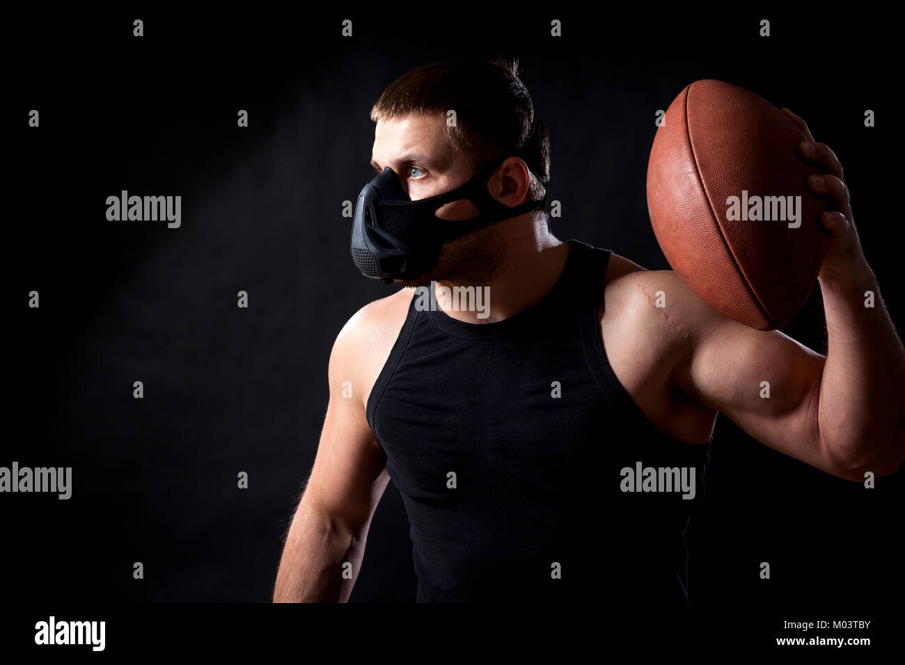 A dark-haired male athlete in a black training mask, a sports shirt ...